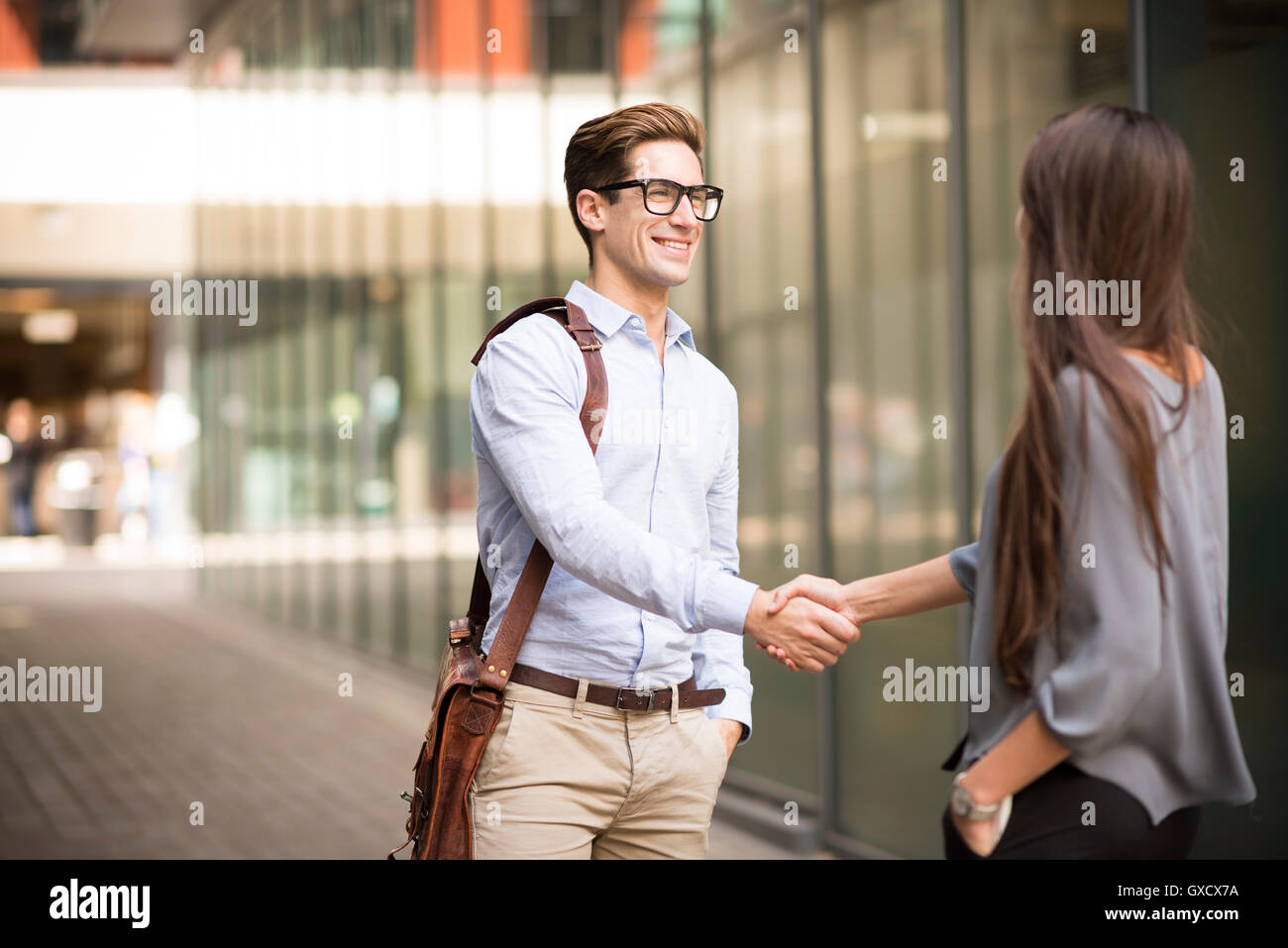 Businessman and woman shaking hands outside office, London, UK Stock ...