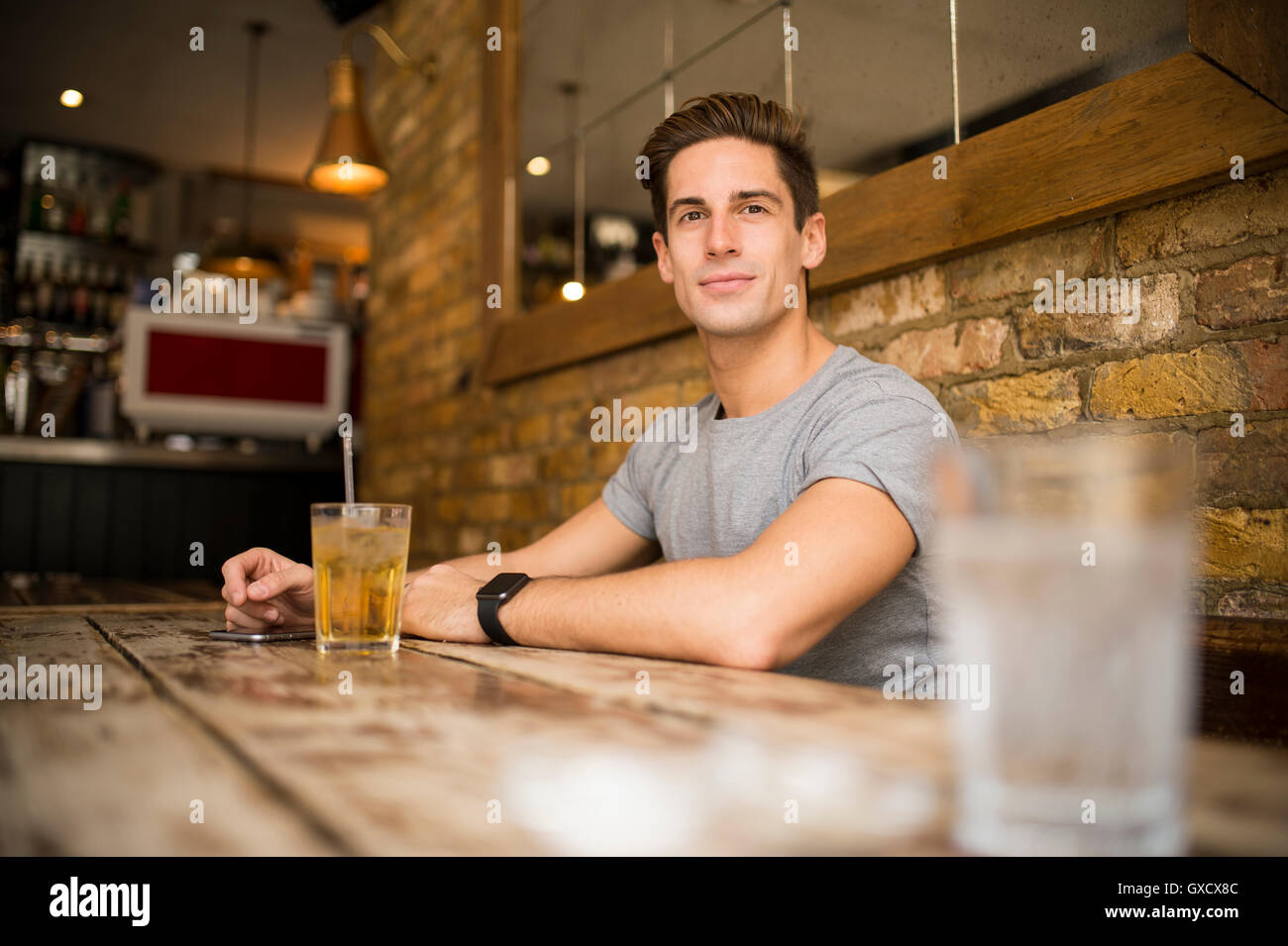 Young man at table in city bar Stock Photo - Alamy
