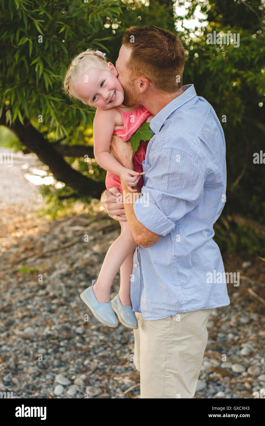 Mid adult man carrying and kissing daughter on cheek at Lake Ontario ... Mid adult man carrying and kissing daughter on cheek at Lake Ontario ...