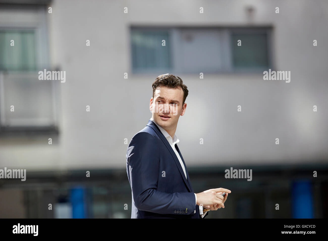 Businessman looking over his shoulder outside office, London, UK Stock ...