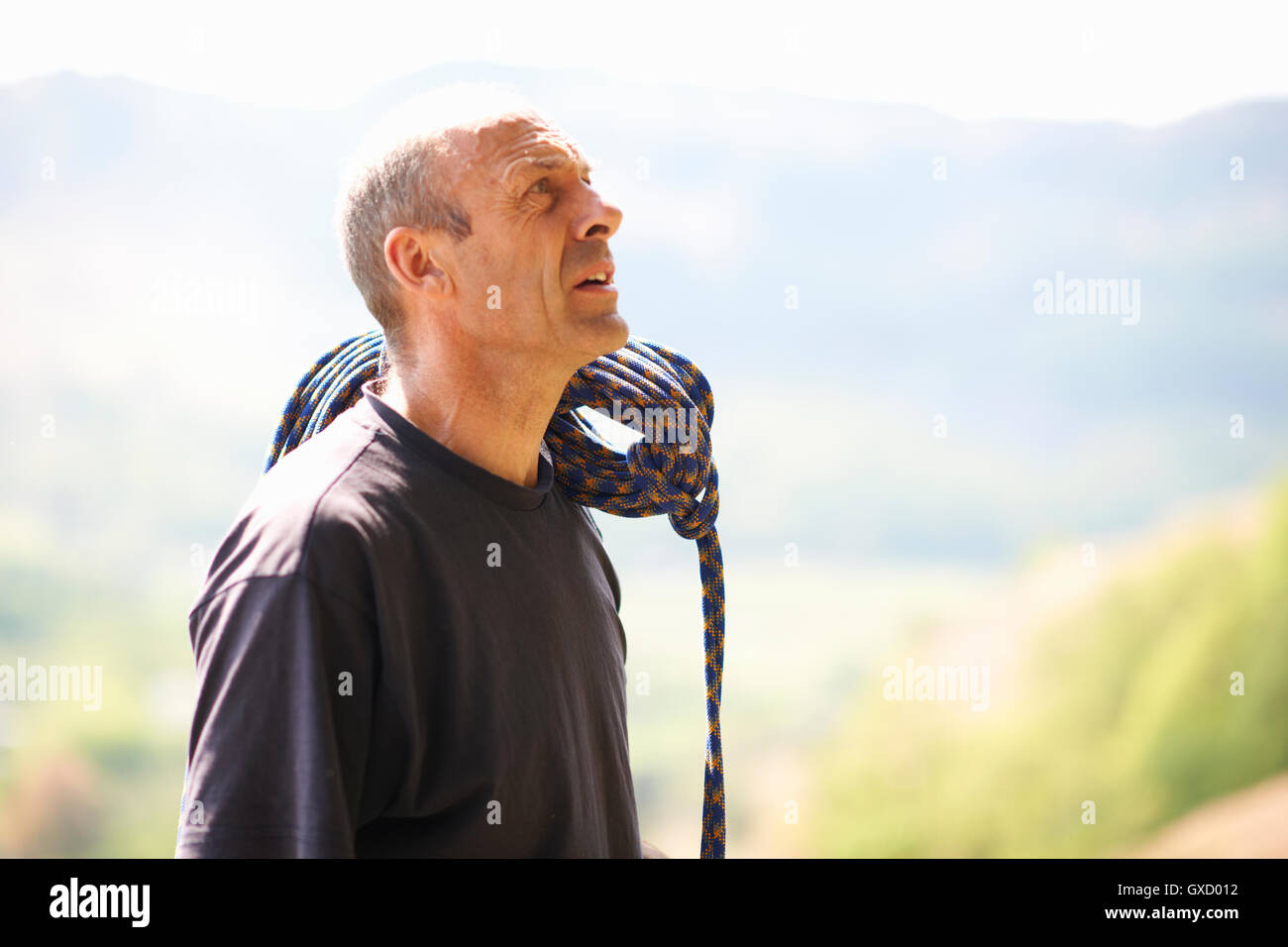 Rock climber carrying rope on shoulder looking up Stock Photo - Alamy