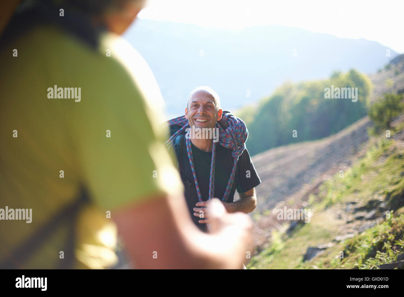 Rock climber carrying rope on shoulders smiling Stock Photo - Alamy