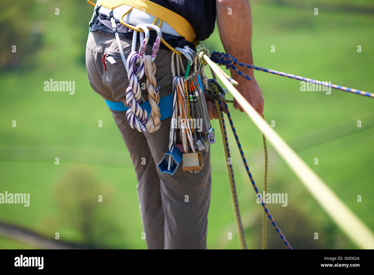 Cropped view of rock climber preparing climbing ropes on safety harness ...