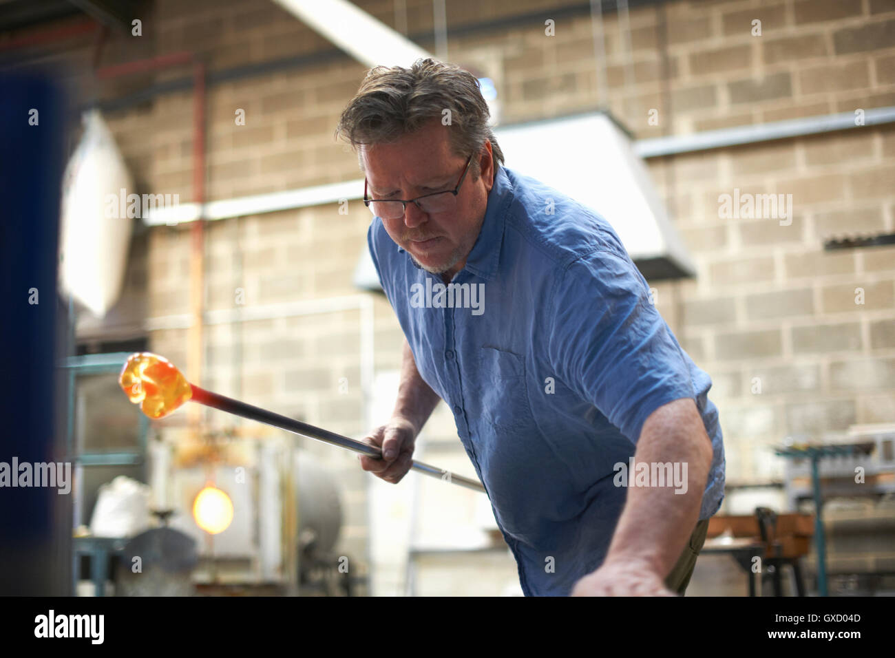 Glassblower in workshop holding blowpipe Stock Photo - Alamy