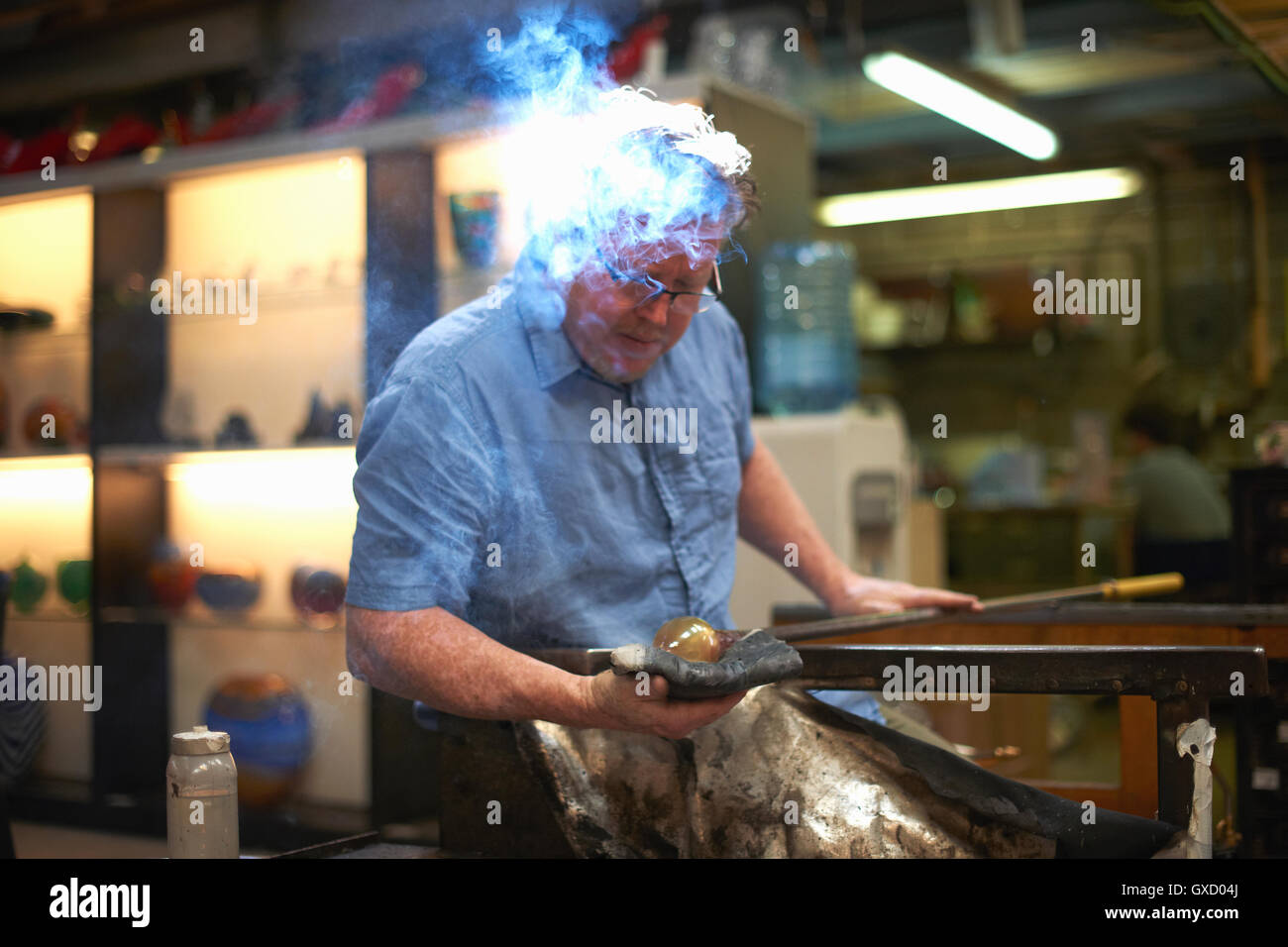 Glassblower in workshop forming molten glass on blowpipe Stock Photo ...