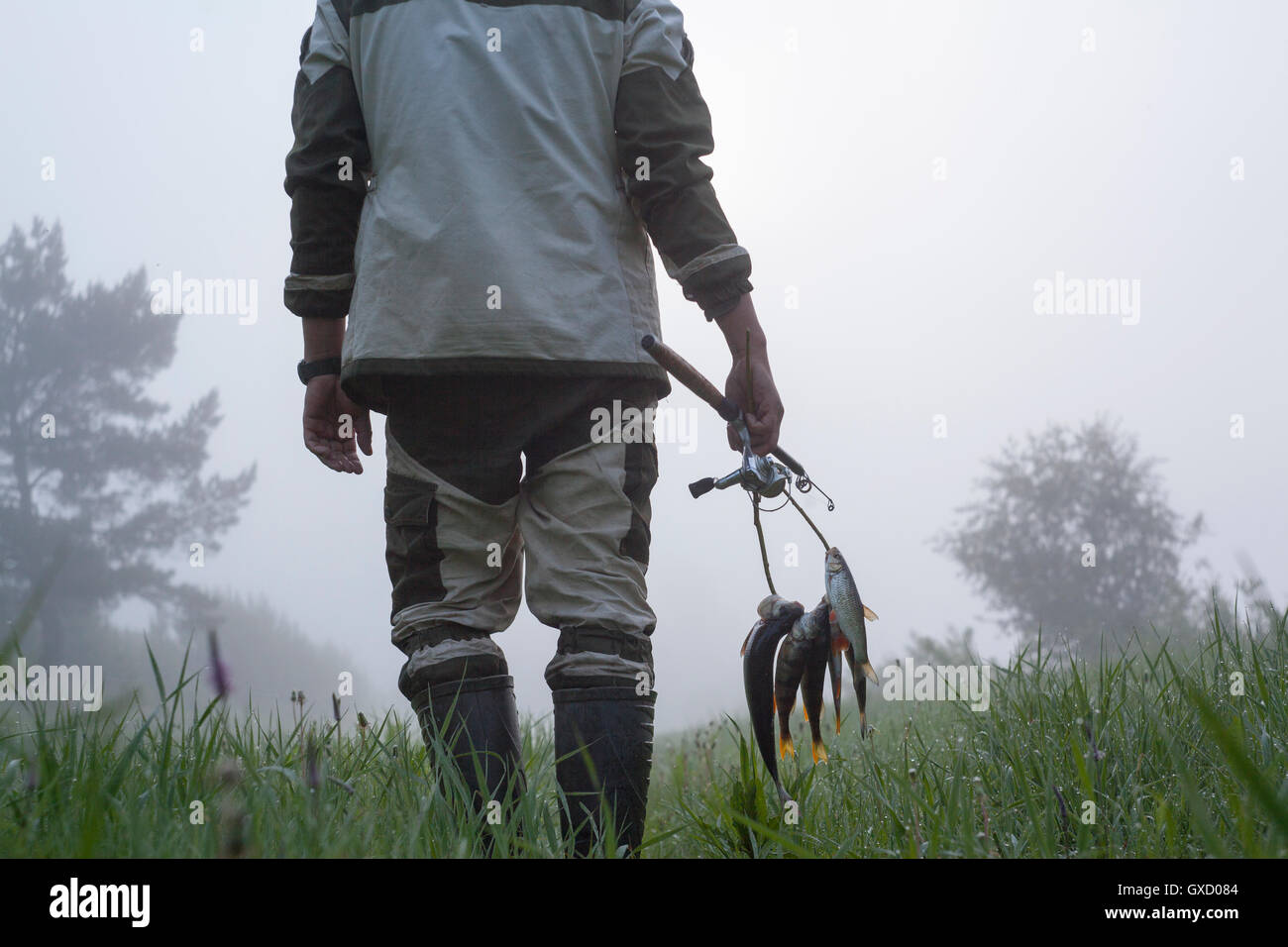 Rear view of fisherman carrying fish Stock Photo - Alamy
