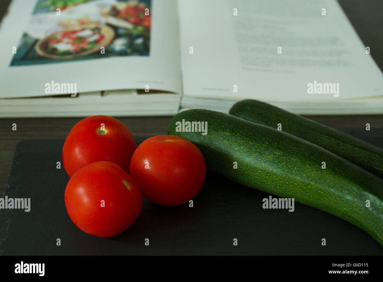 Tomatoes and courgettes with cook book Stock Photo - Alamy