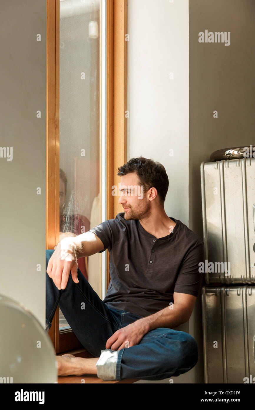 Man sitting looking out of window Stock Photo - Alamy