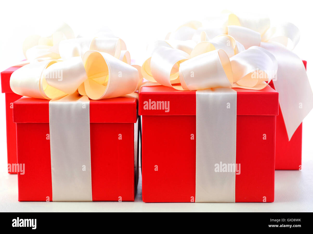 Bright red festive holiday gift boxes beautifully wrapped in cream ...