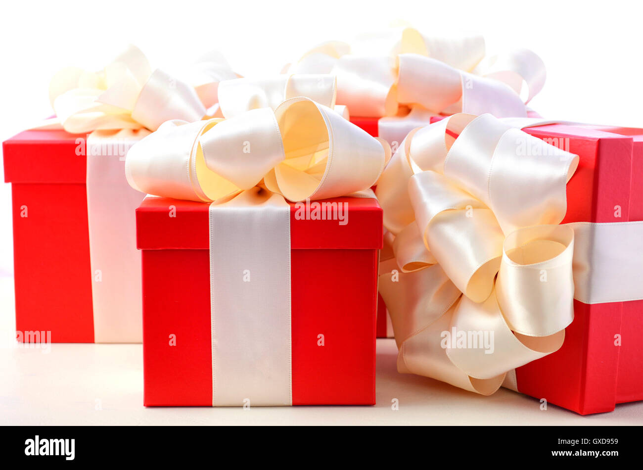 Bright red festive holiday gift boxes beautifully wrapped in cream ...
