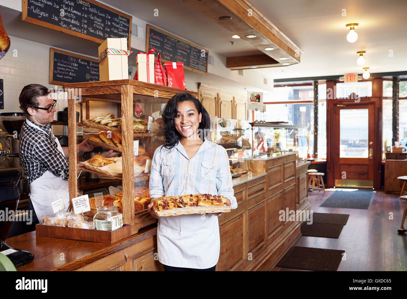Portrait of female worker in bakery holding fresh pastries Stock Photo ...
