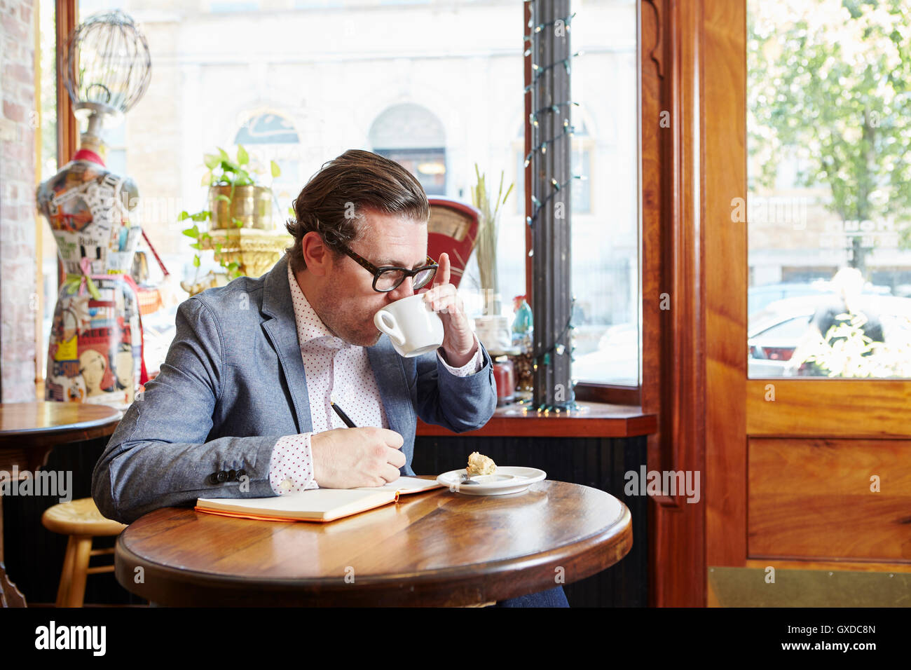Man sitting in cafe, drinking coffee, writing in notebook Stock Photo ...