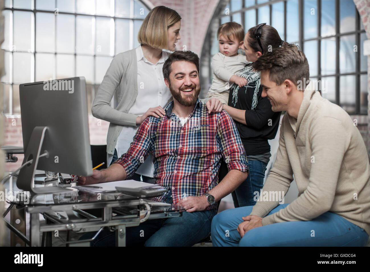 Group of adults sitting around computer having discussion, woman ...