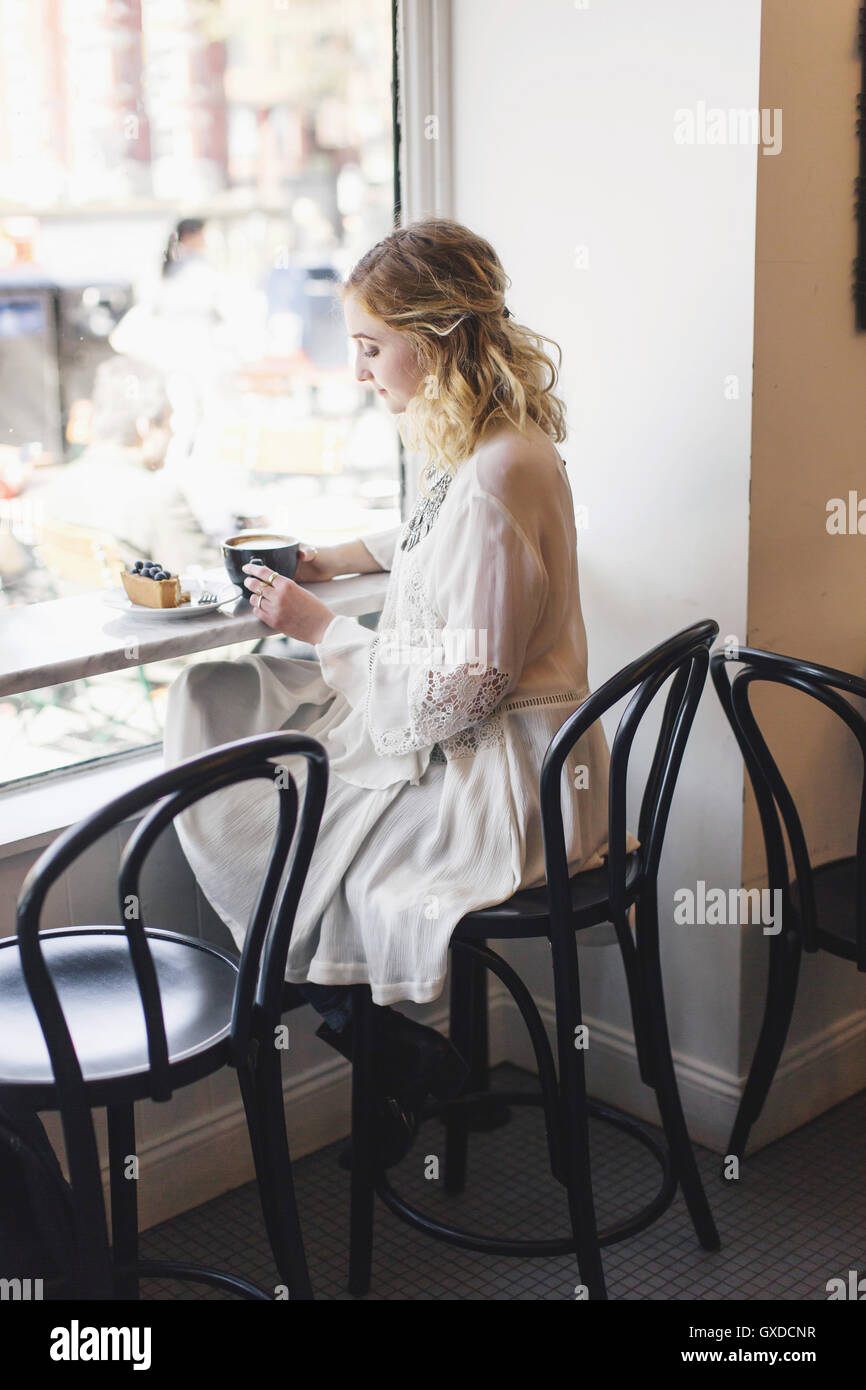 Woman sitting at window seat in coffee shop Stock Photo - Alamy
