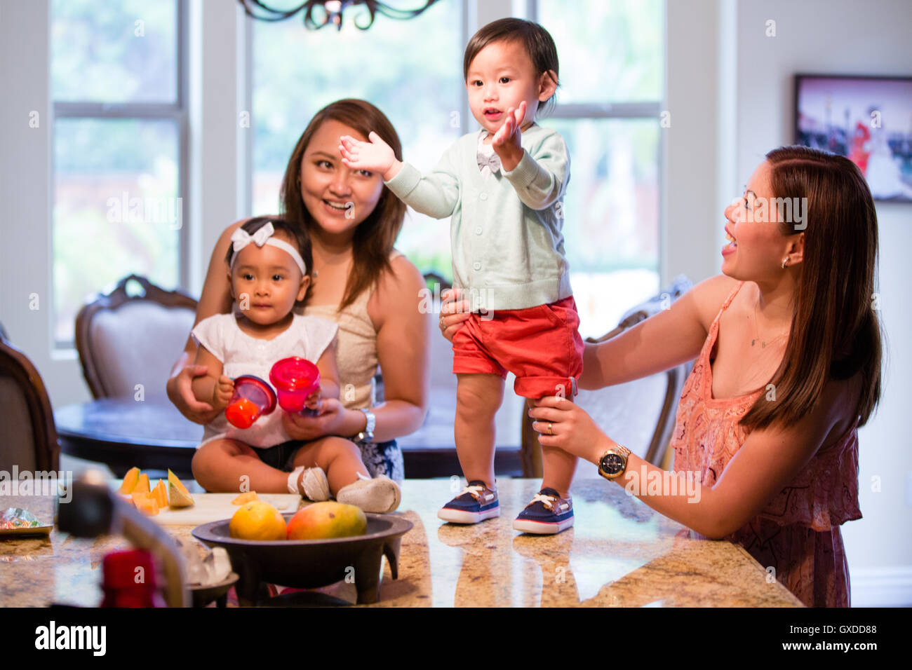 Baby boy standing and clapping hands on dining room table Stock Photo ...