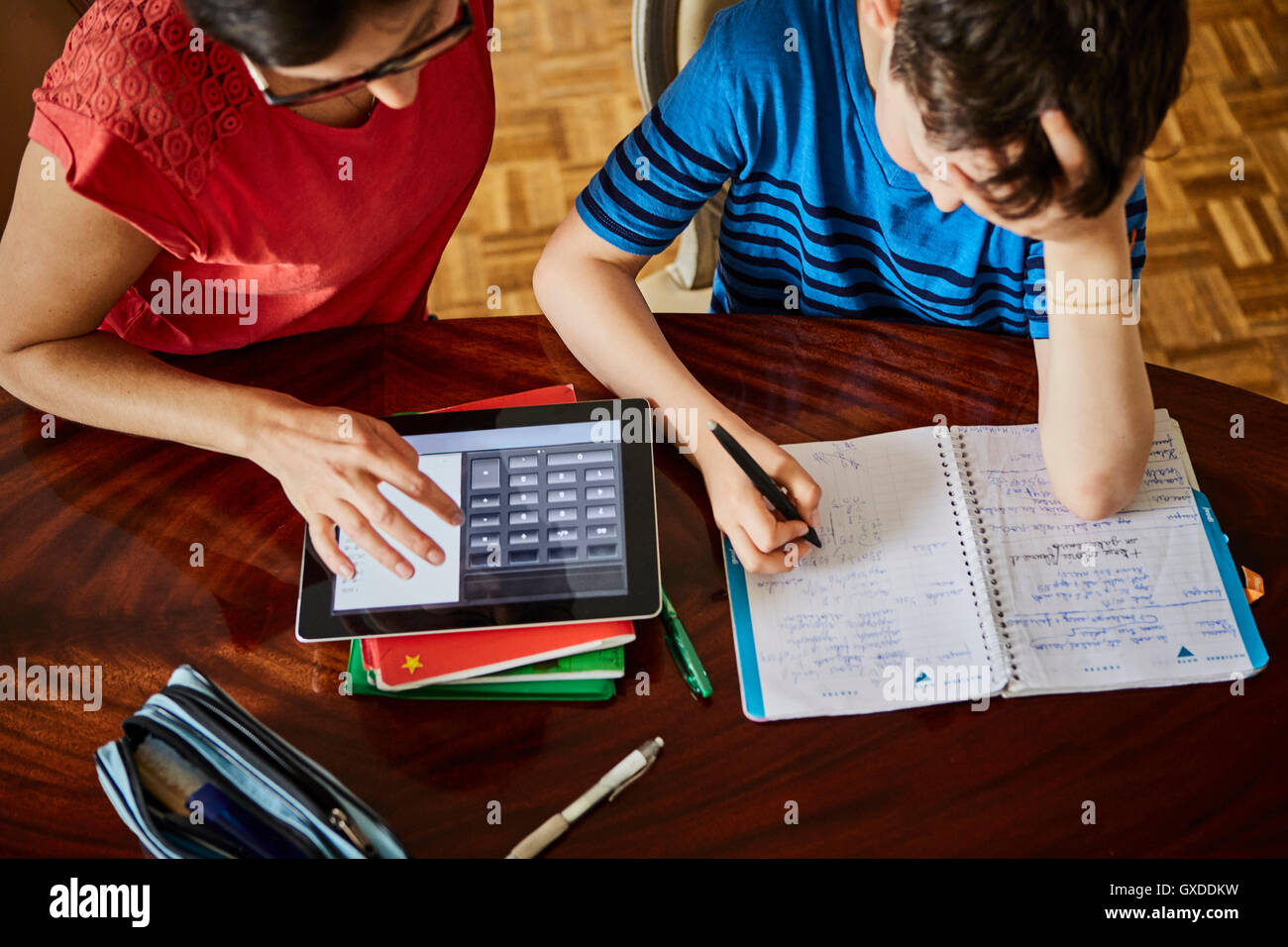 High angle view of mother at dining table helping son with homework ...
