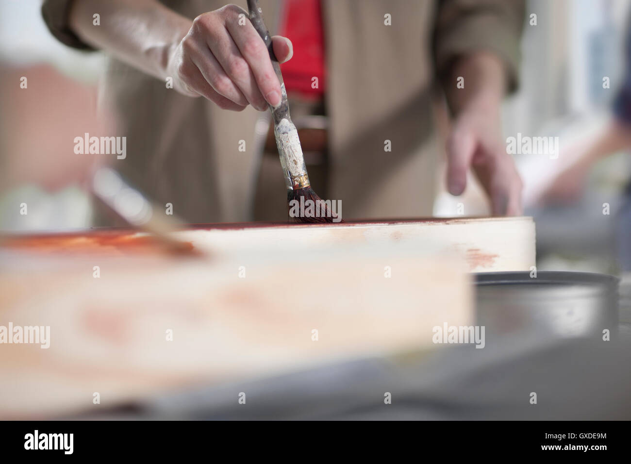 Cropped shot of female carpenter painting wood stain painting in ...