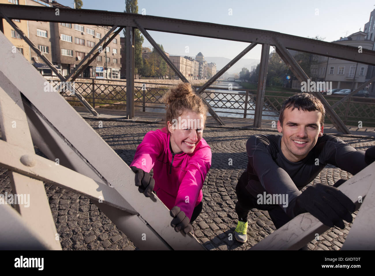jogging couple warming up and stretching before morning running in the ...