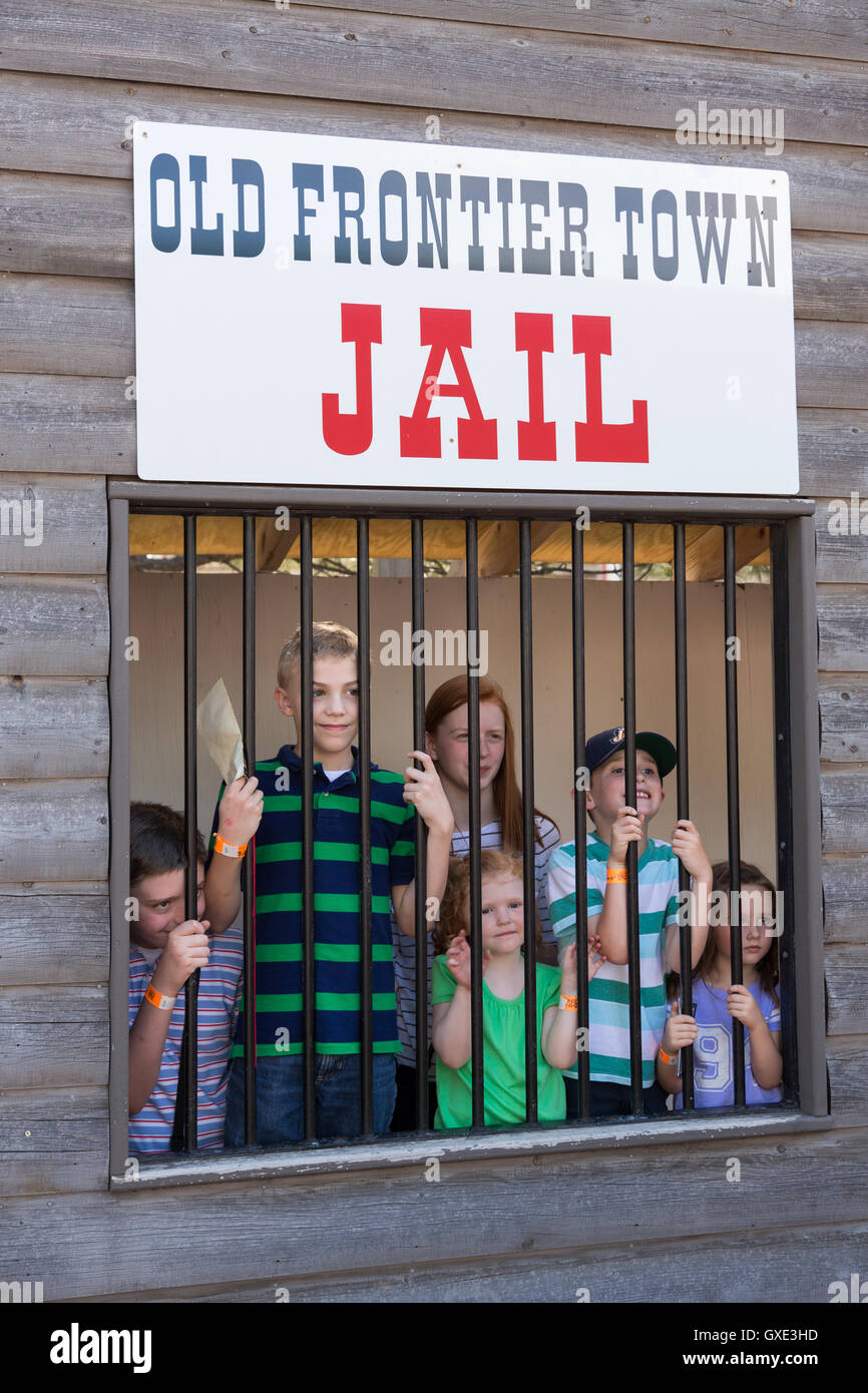 Children pose in the Old Frontier Town jail from behind bars during ...