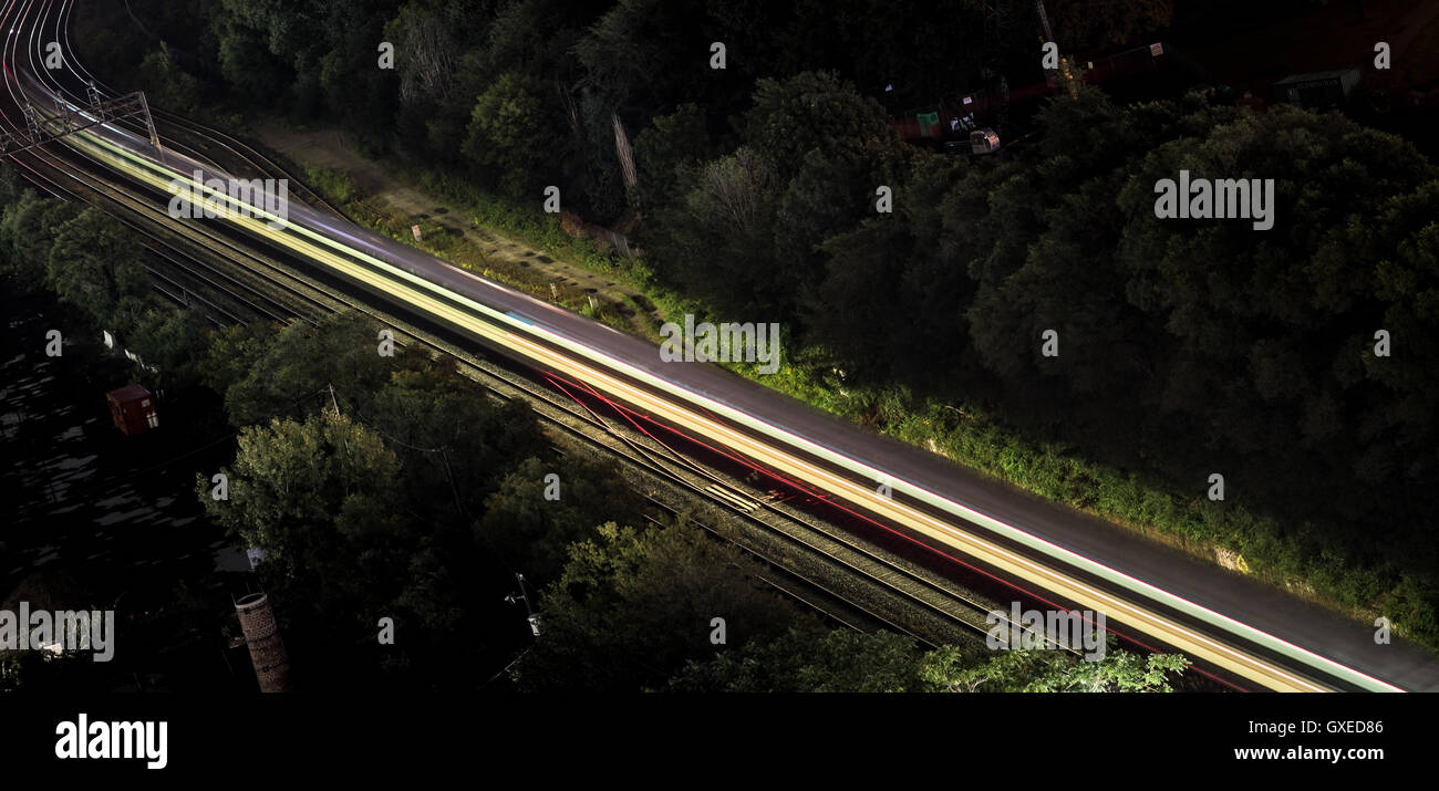 Red rails as passing subway train melts into light streak. Long ...