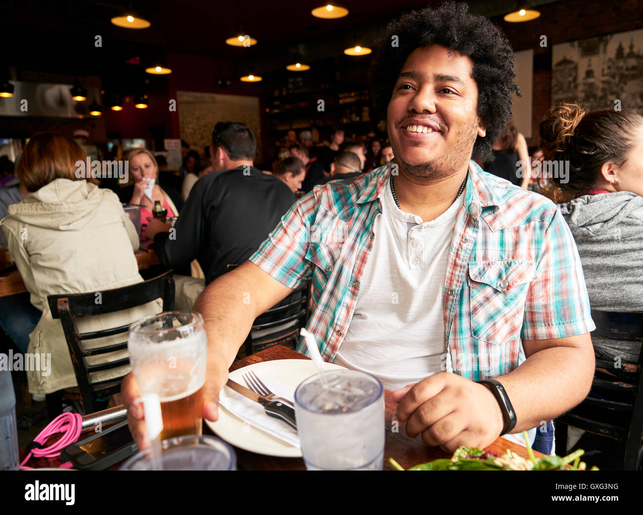 Smiling man drinking beer in restaurant Stock Photo - Alamy