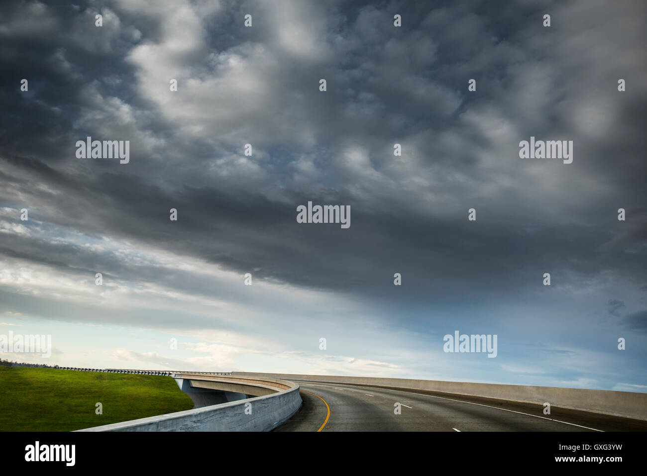 Clouds over winding highway Stock Photo - Alamy