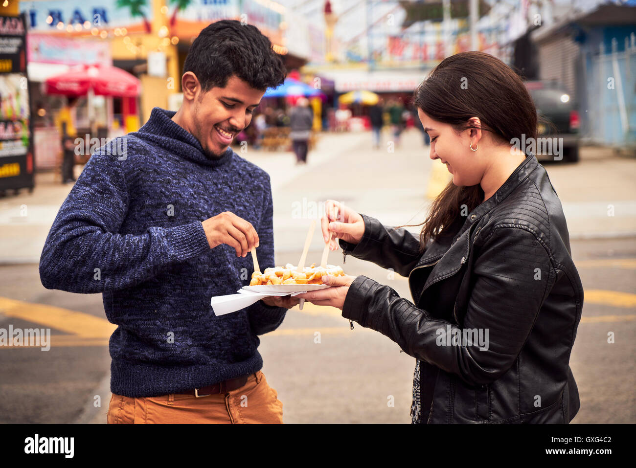 Couple sharing plate of food at amusement park Stock Photo - Alamy