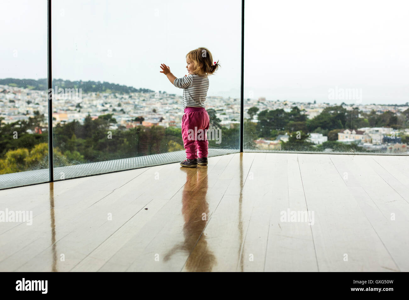 Curious Caucasian girl leaning on window admiring cityscape Stock Photo ...