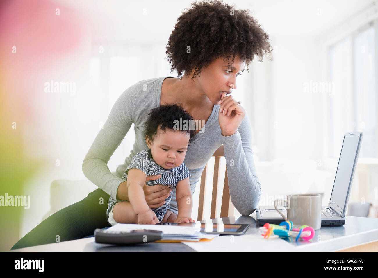 Mother holding baby son worrying about laptop Stock Photo - Alamy