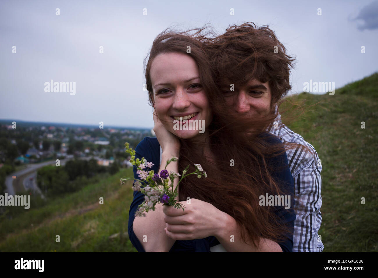 Caucasian couple hugging on hill Stock Photo - Alamy