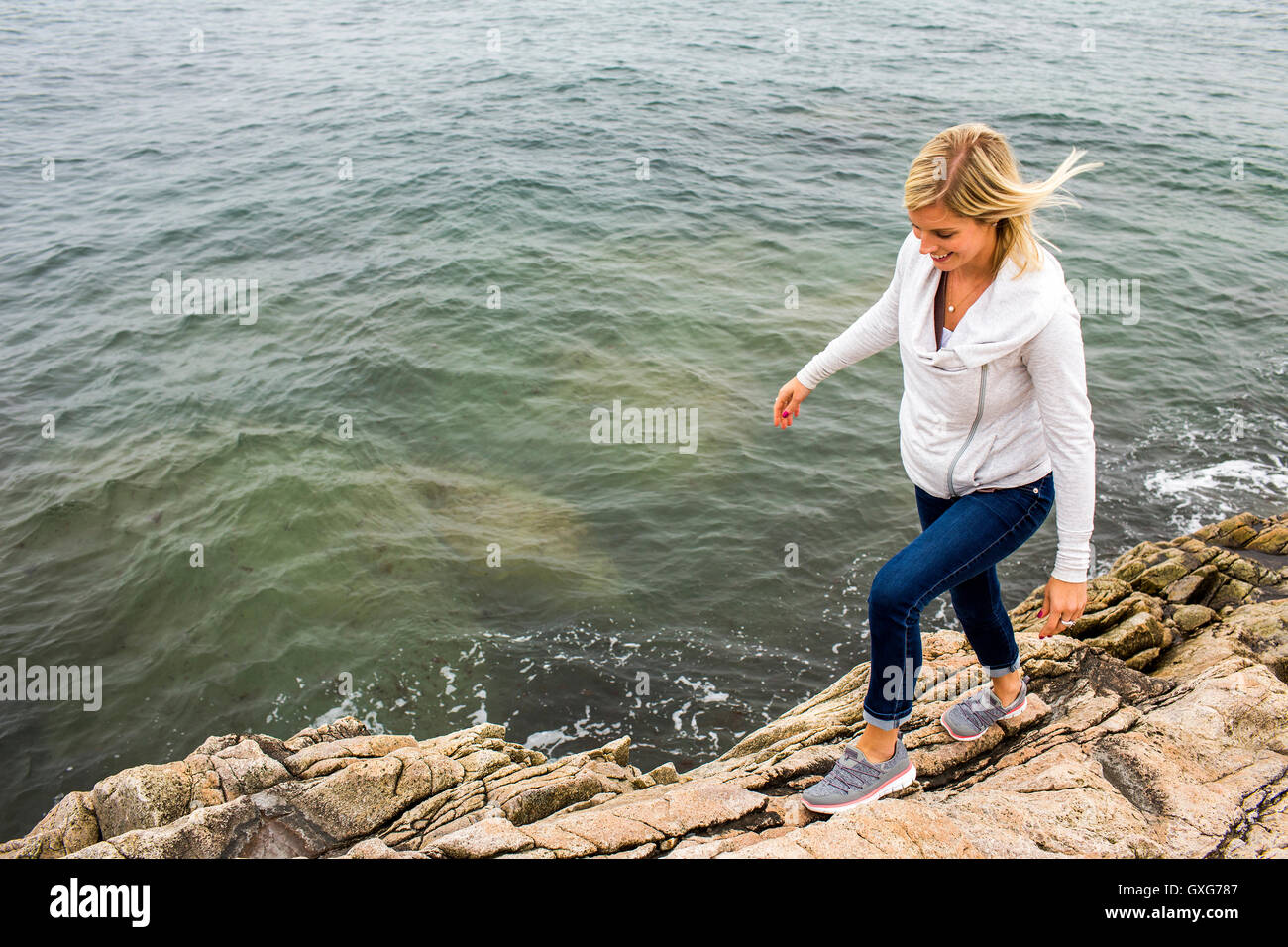 Caucasian woman walking on rocks at ocean Stock Photo - Alamy