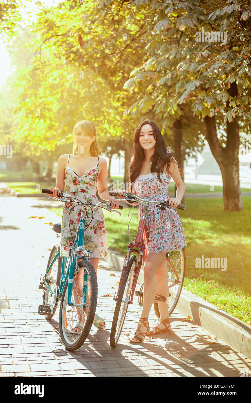 The two young girls with bicycles in park Stock Photo - Alamy