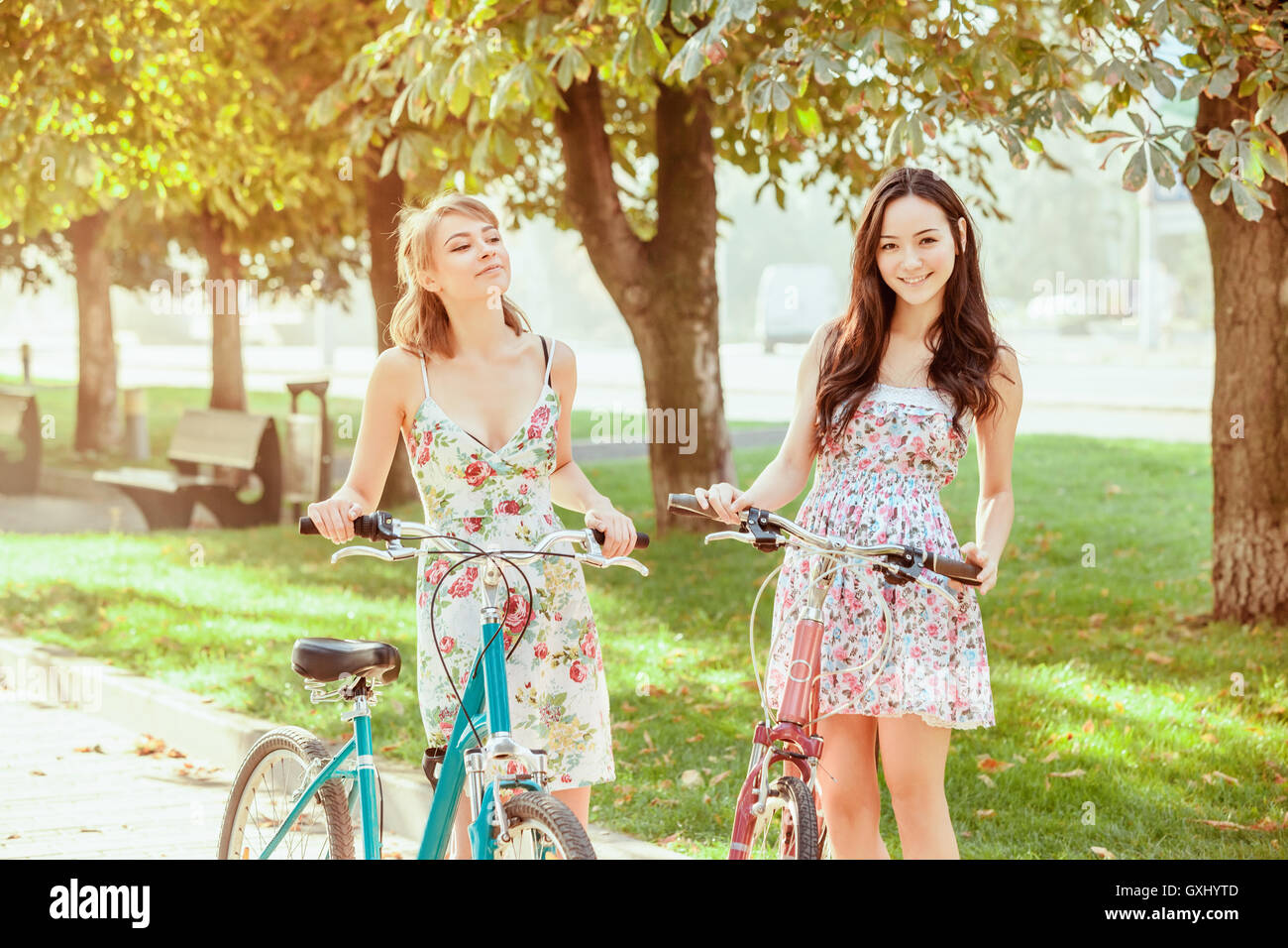 The two young girls with bicycles in park Stock Photo - Alamy
