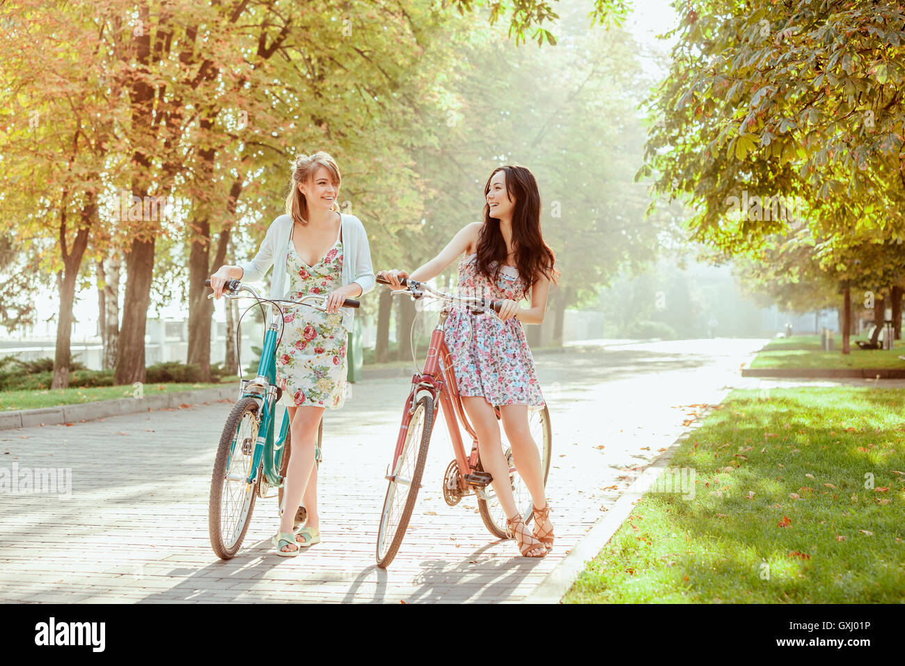 The two young girls with bicycles in park Stock Photo - Alamy