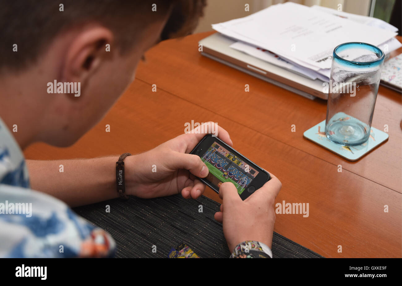 Teenage boy playing a game on his Apple iPhone 5s mobile phone Stock ...