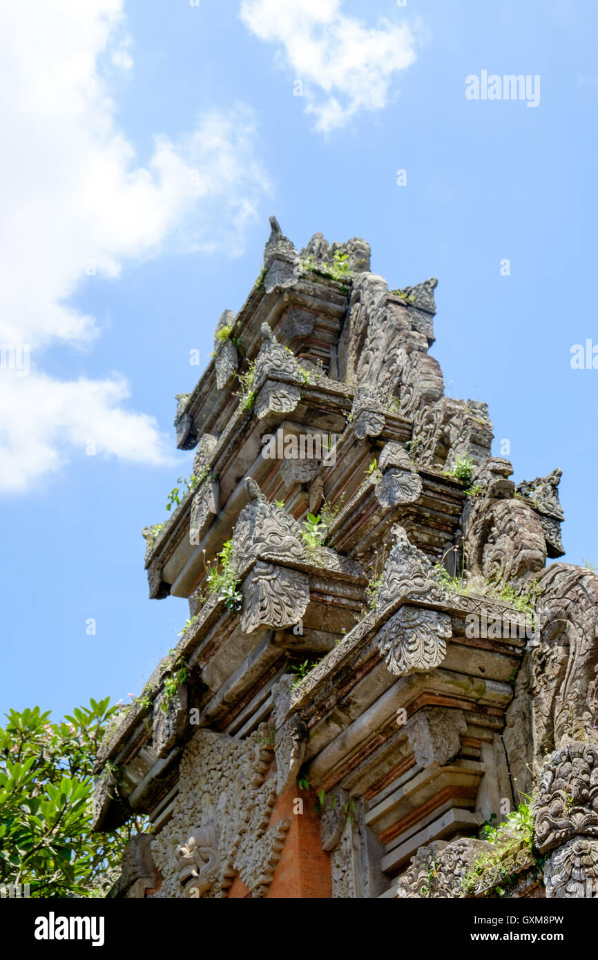 Ornate Balinese temple gate, weathered by time, stands against a bright ...