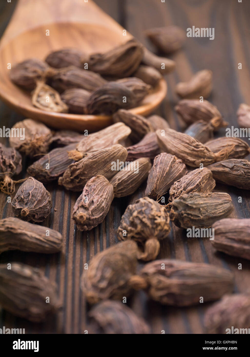 Black cardamom pods in the wooden spoon on the dark wooden textured ...