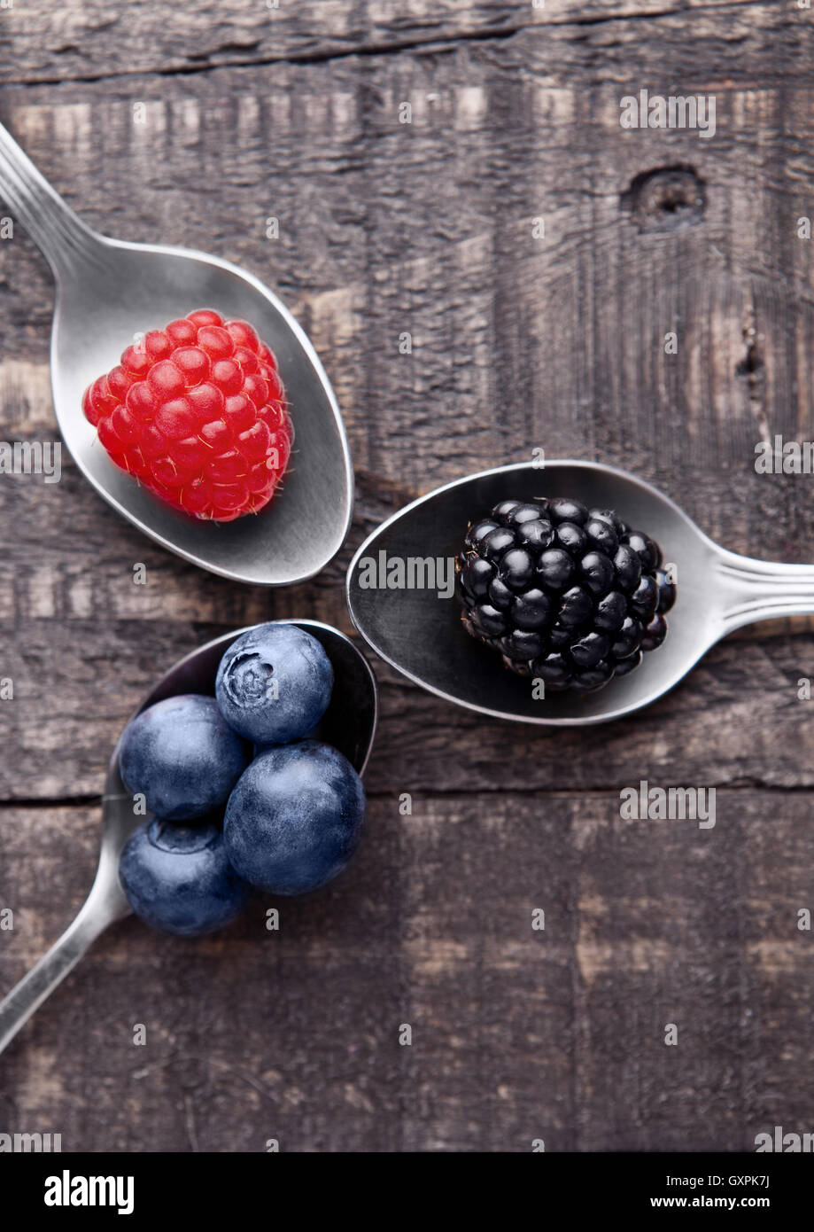 Raspberry blueberry and blackberry on spoon and wooden table. Still ...