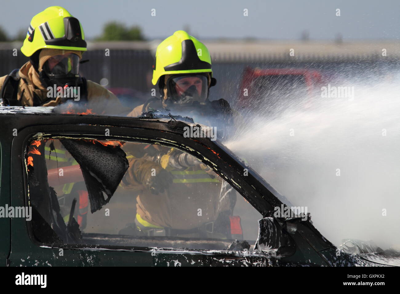 Firefighters wearing breathing apparatus tackle a vehicle fire using ...
