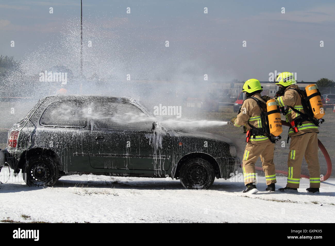 Firefighters wearing breathing apparatus tackle a vehicle fire using ...