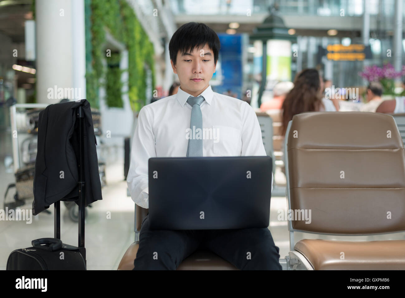 Asian young business traveler using laptop computer in airport lounge ...