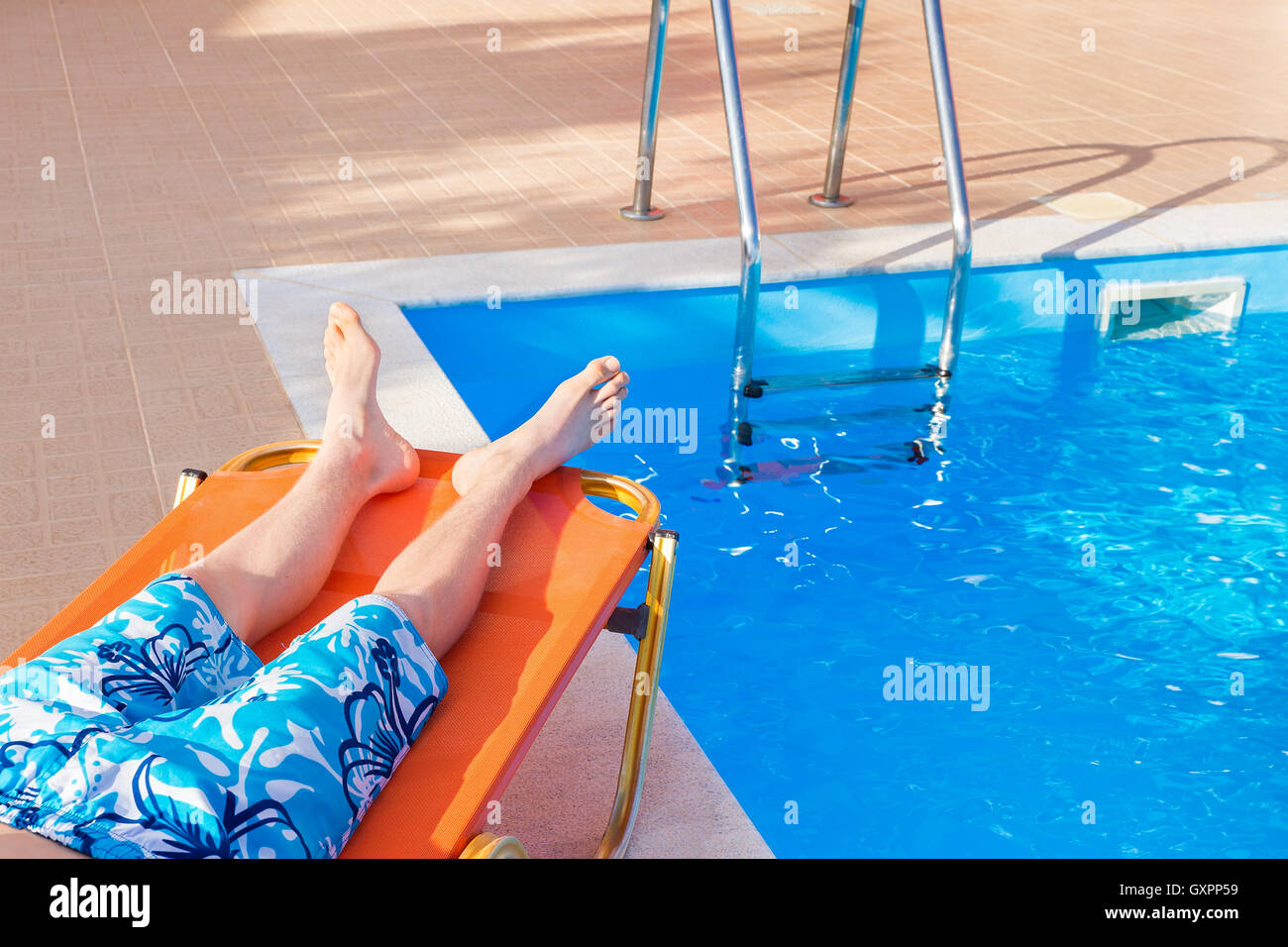 Caucasian teenage boy lying on stretcher near blue swimming pool Stock ...
