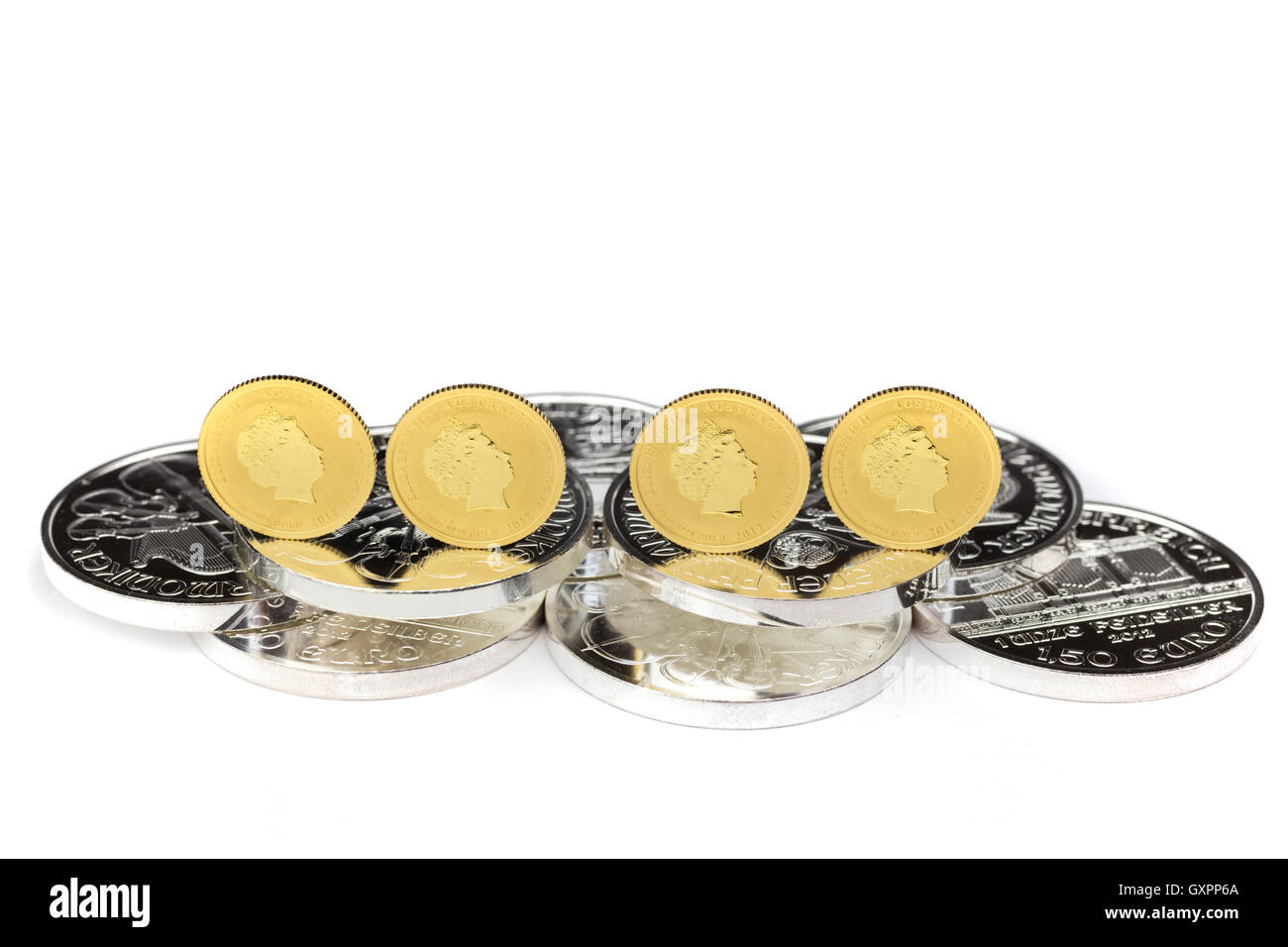 Four gold coins standing on silver coins isolated on white background ...