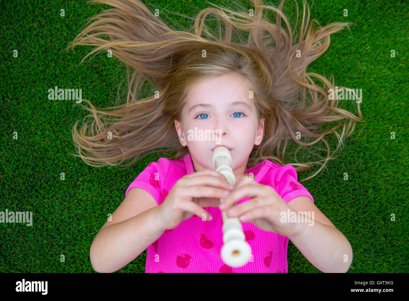 Blond kid children girl playing flute lying on grass Stock Photo - Alamy