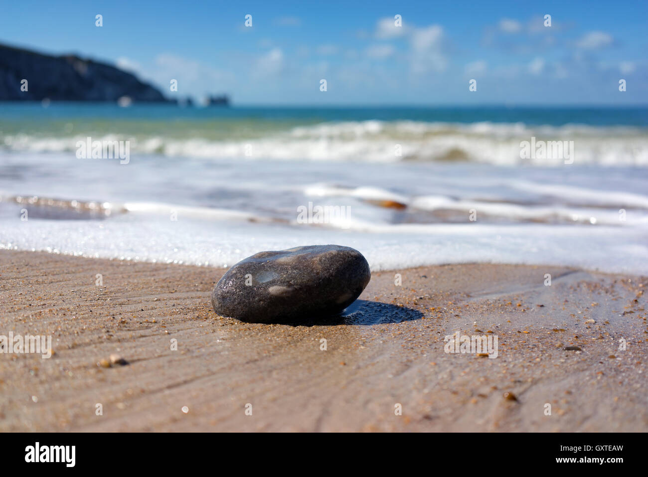 Pebble on a beach with coastline and waves in the background Stock ...