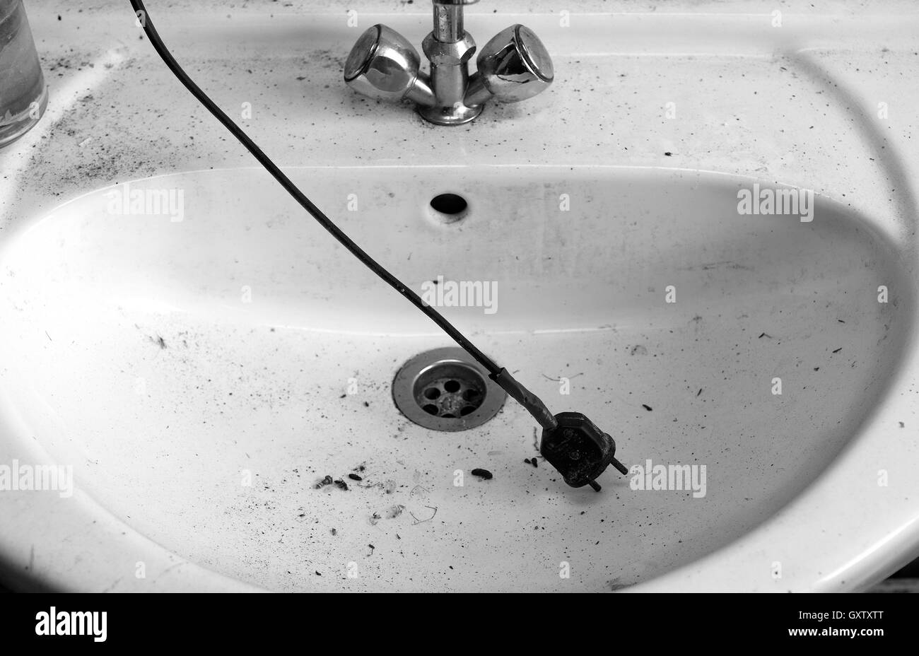 Closeup of a damaged sink with electric cable out of use. In black and ...