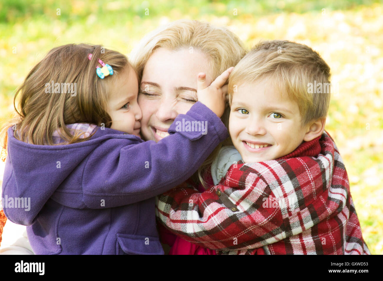 Two children hugging mother Stock Photo - Alamy