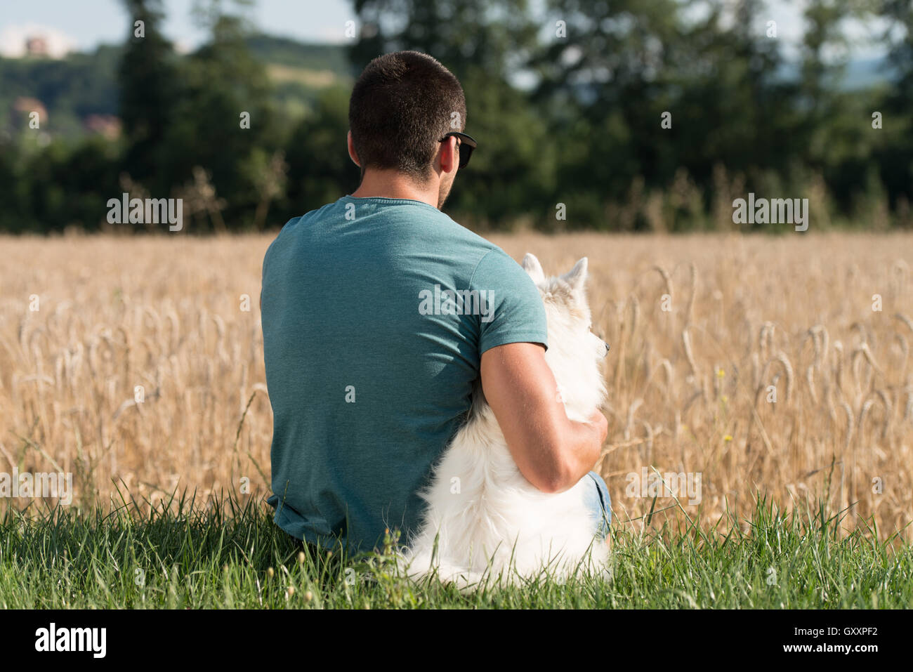 Young Man Sitting With Dog German Spitz In Harvested Field Stock Photo ...
