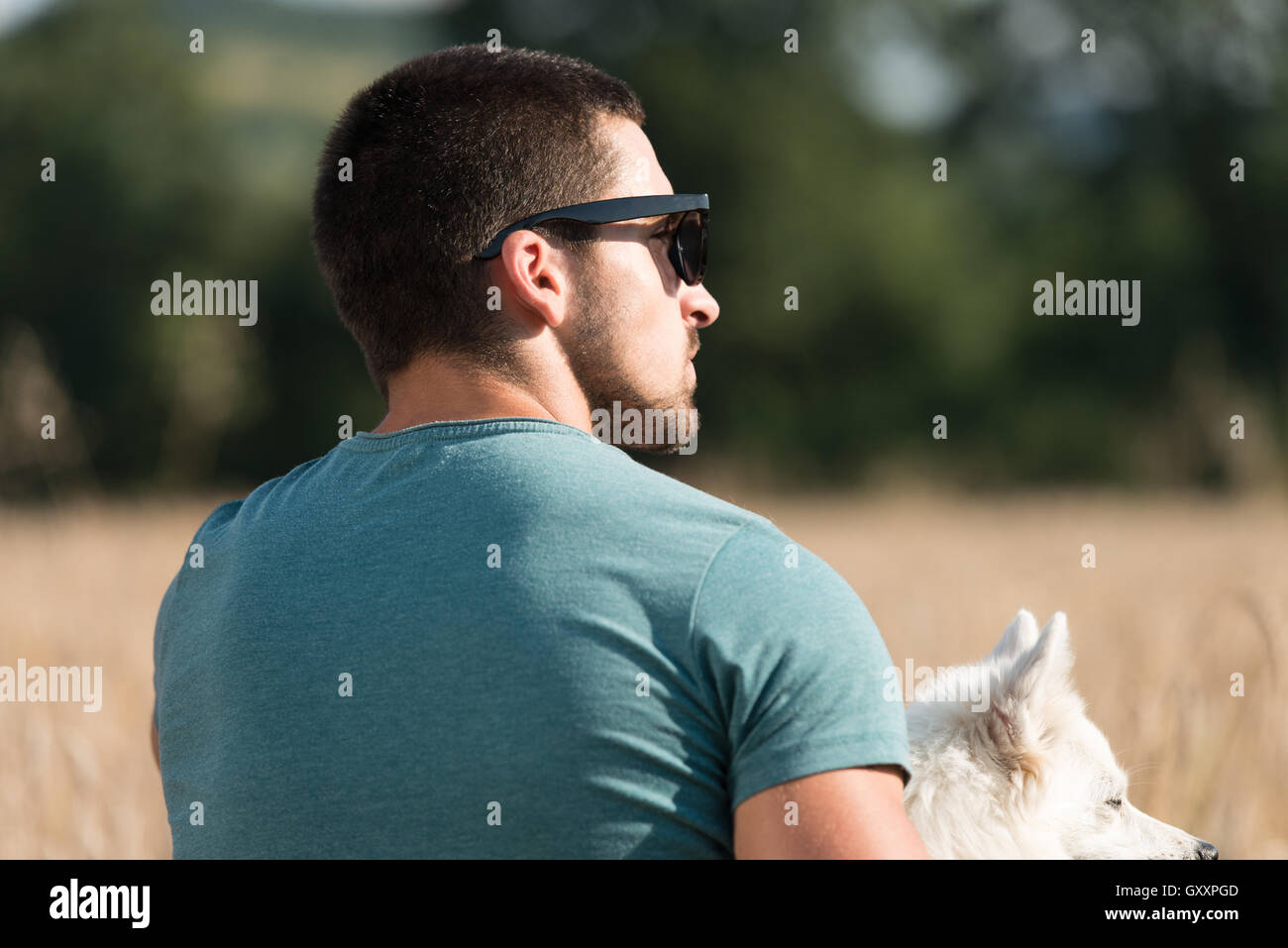 Young Man Sitting With Dog German Spitz In Harvested Field Stock Photo ...