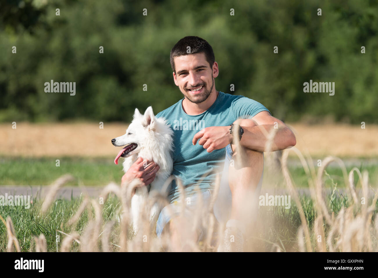 Young Man Sitting With Dog German Spitz In Harvested Field Stock Photo ...